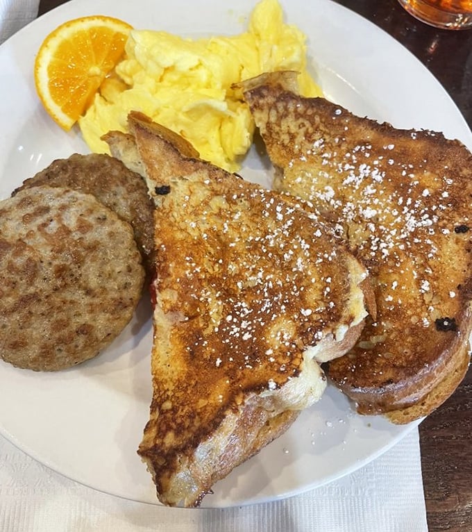 Golden French toast dusted with powdered sugar alongside fluffy scrambled eggs. Breakfast's greatest hits album, with sausage playing backup.