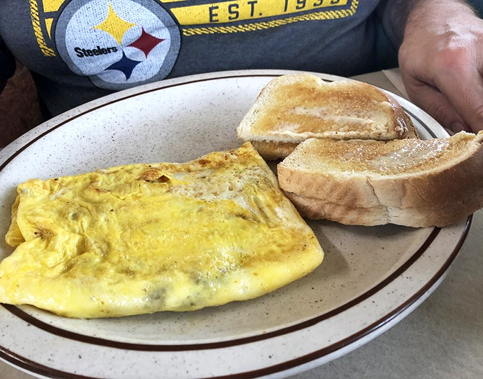 
Behold the cheese omelet&mdash;sunshine yellow, perfectly folded, and paired with toast that's achieved that magical butter-to-crunch ratio only diners seem to master.