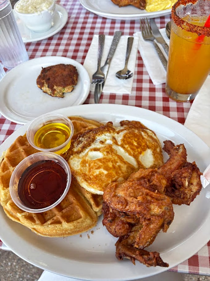 The holy trinity of diner perfection: golden-brown chicken, fluffy waffles, and those two magical cups of syrup and butter.