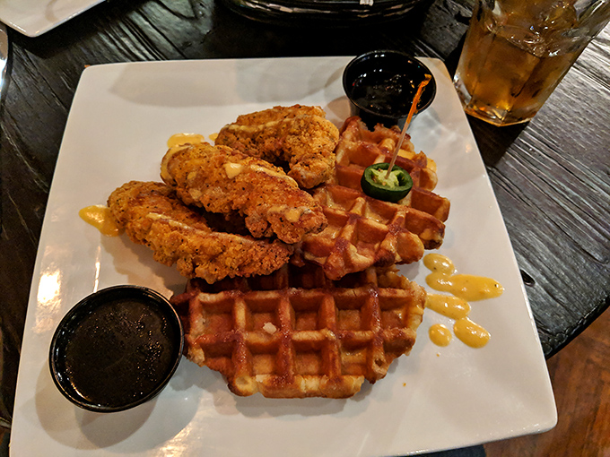 Golden-brown chicken perched atop Belgian waffles like royalty on a throne, with maple syrup waiting in the wings for its grand entrance.