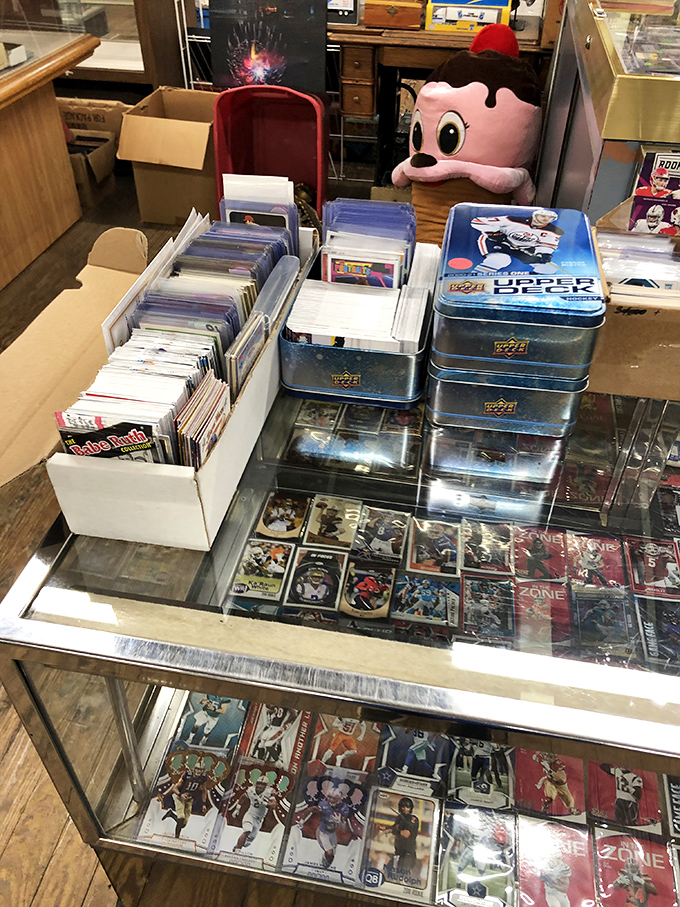 Sports card heaven! Where childhood memories and potential retirement funds sit side by side under glass, guarded by a pink mascot with questionable fashion sense.
