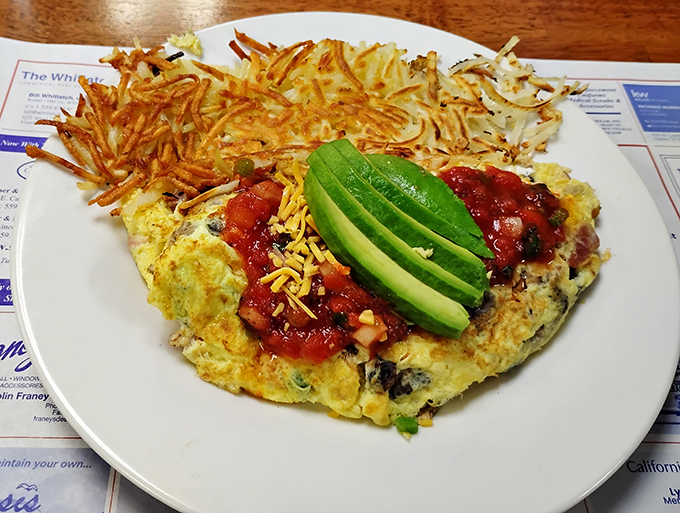 This isn't just an omelet – it's a California dream with perfectly crispy hash browns, vibrant avocado slices, and salsa that wakes up your taste buds better than any alarm clock.