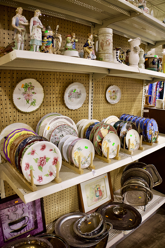 Grandma's china cabinet exploded here! Decorative plates with floral patterns and vintage figurines await their second chance at dinner party stardom.