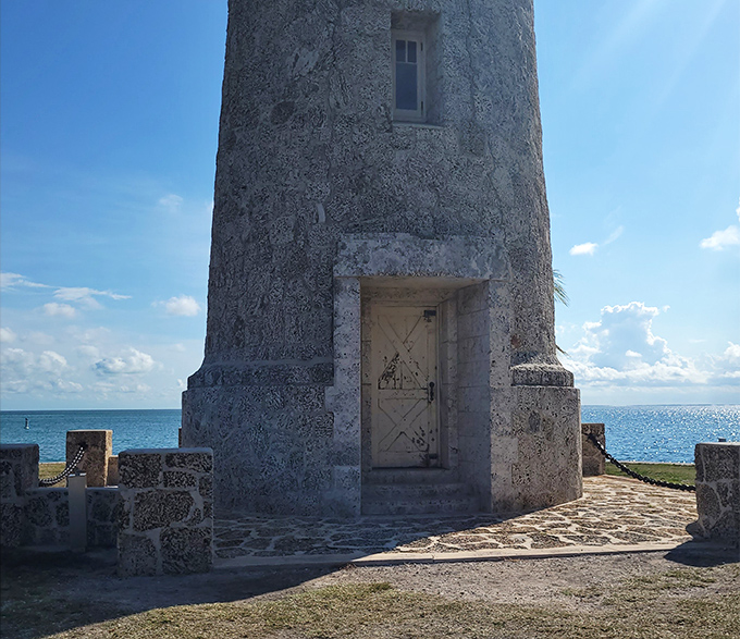 The lighthouse entrance beckons with rustic charm, its weathered door holding stories of storms weathered and sunsets witnessed across countless Florida summers.