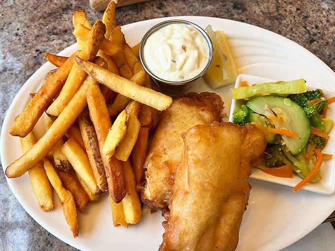 Golden-battered fish that shatters with each bite, paired with fries that achieve the perfect crisp-to-fluffy ratio. The vegetables? A valiant attempt at virtue.