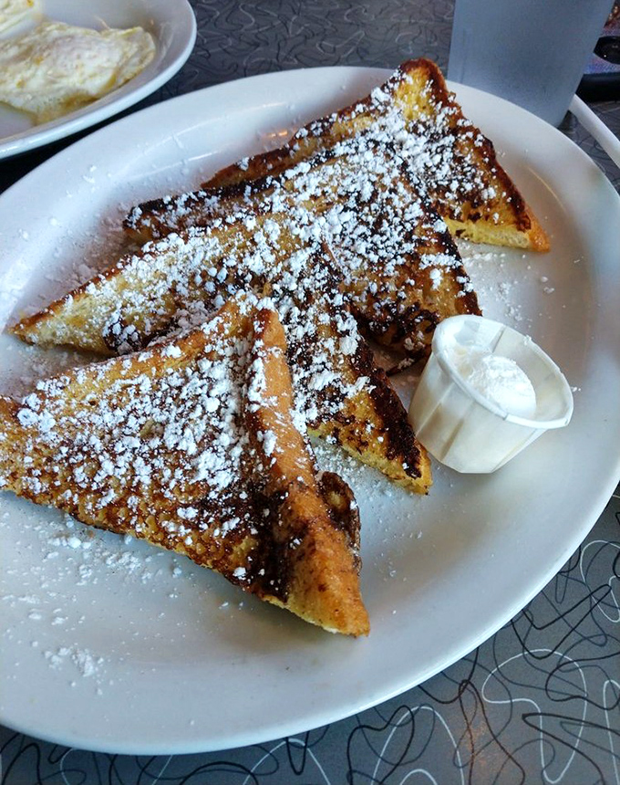 The star of the show: French toast dusted with powdered sugar like fresh Florida snow, golden-crisp edges giving way to custardy perfection inside.