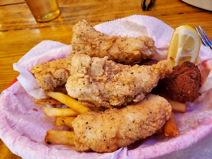 Golden-fried grouper that shatters with each bite, served unpretentiously in a paper-lined basket with fries. No foam, no tweezers, just seafood done right.