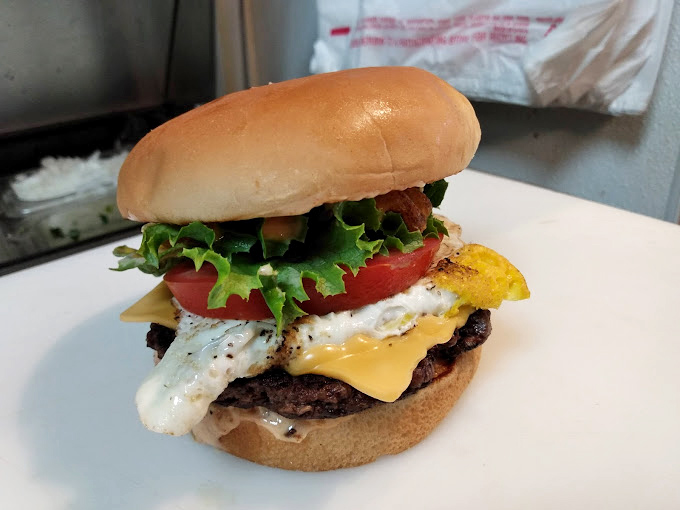 Behold the California Burger in all its glory. That perfect melty cheese cascade, the vibrant veggies, and a patty that makes fast-food chains weep with inadequacy.