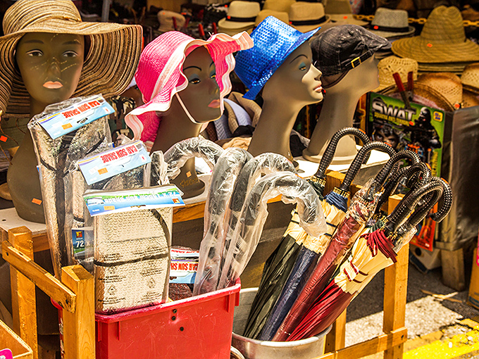 Mannequin heads modeling colorful sun hats stand guard over umbrellas and accessories, ready for Florida's unpredictable "sunshine and shower" forecasts.