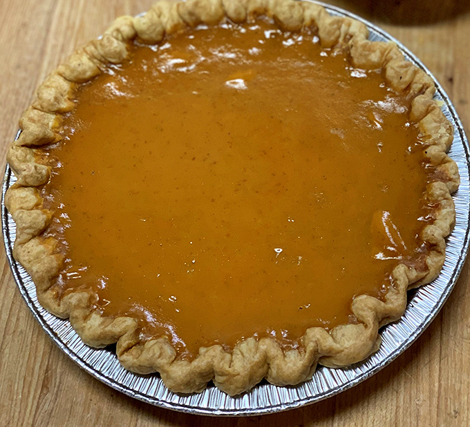 This pumpkin pie isn't just dessert; it's an amber pool of autumn memories with a crust crimped by hands that clearly understand the meaning of "flaky perfection."