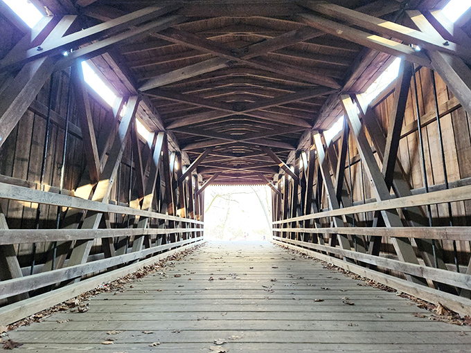 Architectural poetry in wood: Inside the bridge, sunlight streams through slats creating a dance of light and shadow across the weathered planks.