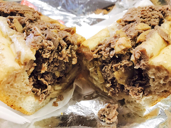 Behold the cross-section of perfection: a cheesesteak so juicy it demands a stack of napkins and zero shame.