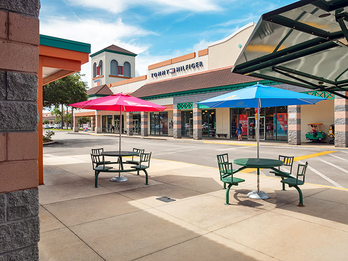 Colorful umbrellas shade outdoor seating areas where strategic shoppers plot their next move or partners wait patiently, contemplating the mysterious economics of "saving money by spending it."