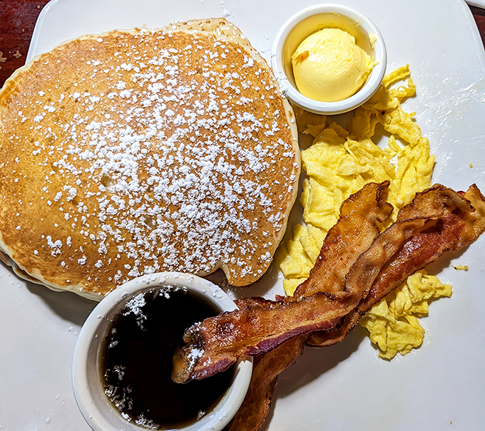Pancakes so fluffy they need their own ZIP code, paired with perfectly crisp bacon and eggs that define breakfast bliss.
