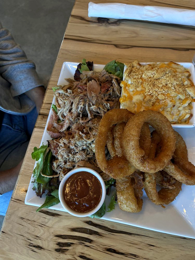 Pulled pork perfection on full display &ndash; tender strands of smoky meat alongside golden onion rings and mac & cheese. This plate is Pennsylvania's answer to barbecue bliss.