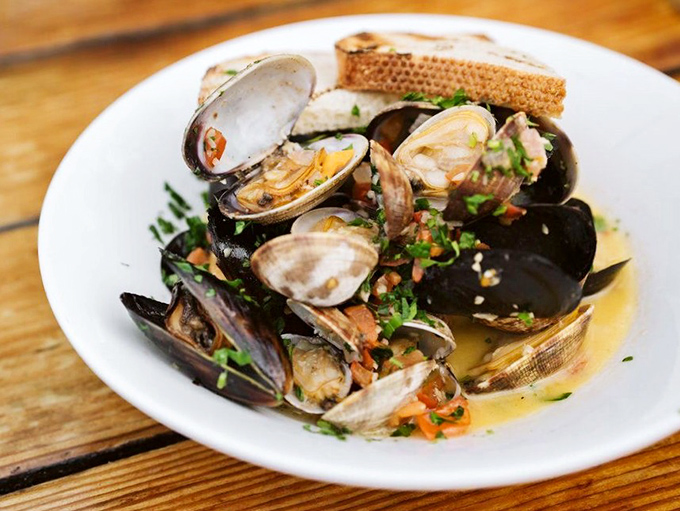These mussels and clams aren't just seafood; they're a briny chorus line performing in a buttery broth that demands to be sopped up with that crusty bread.