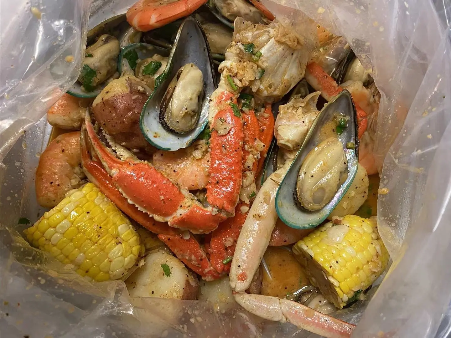 A clear plastic bag becomes a portal to seafood nirvana—crab legs, mussels, and corn swimming in seasoned glory. No fancy plating needed when it tastes this good.