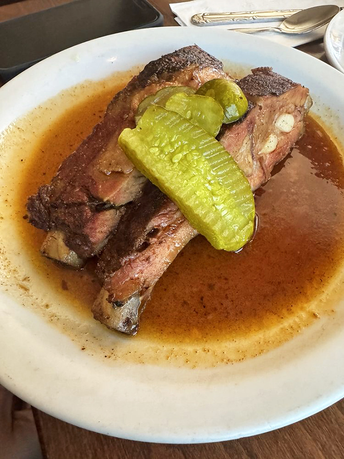 These ribs aren't just falling off the bone—they're practically filing for independence. The pickle adds that perfect acidic counterpoint to the smoky richness.