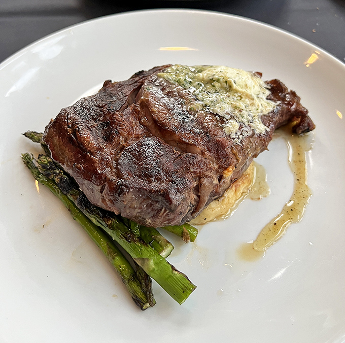 This isn't just a steak; it's a masterpiece of meat artistry resting on a bed of grilled asparagus, waiting to make your taste buds sing.