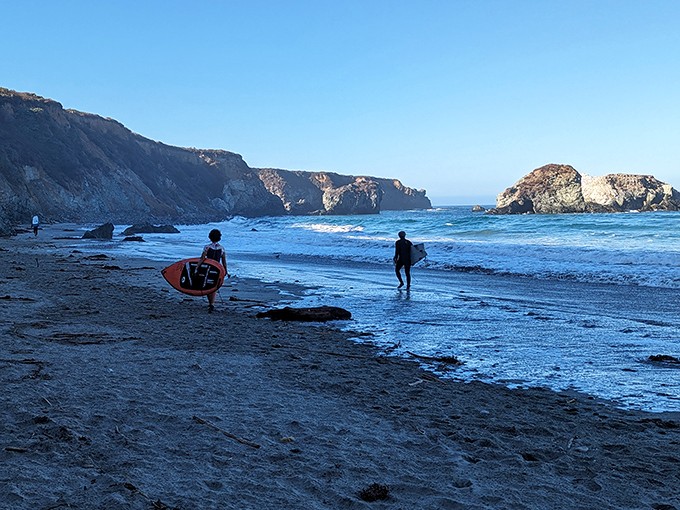 Dawn patrol surfers chase the perfect wave, silhouetted against cliffs that have witnessed this dance between human and ocean for generations.