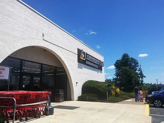 Sunshine bathes the Community Aid storefront, where red shopping carts stand ready for your thrifting adventure.