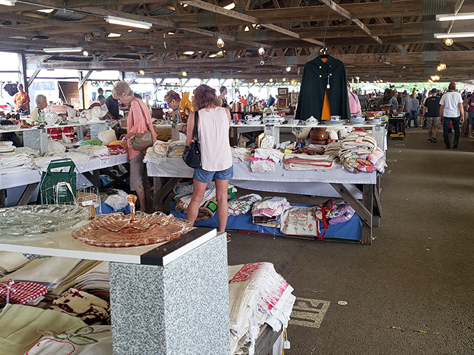 Treasure hunting indoors! Shoppers browse tables piled high with linens and household goods at Renninger's, where every aisle promises new discoveries.