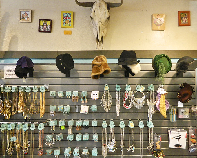 The accessories wall transforms fashion fossils into statement pieces. That buffalo skull watching over vintage hats and jewelry? The ultimate secondhand guardian.