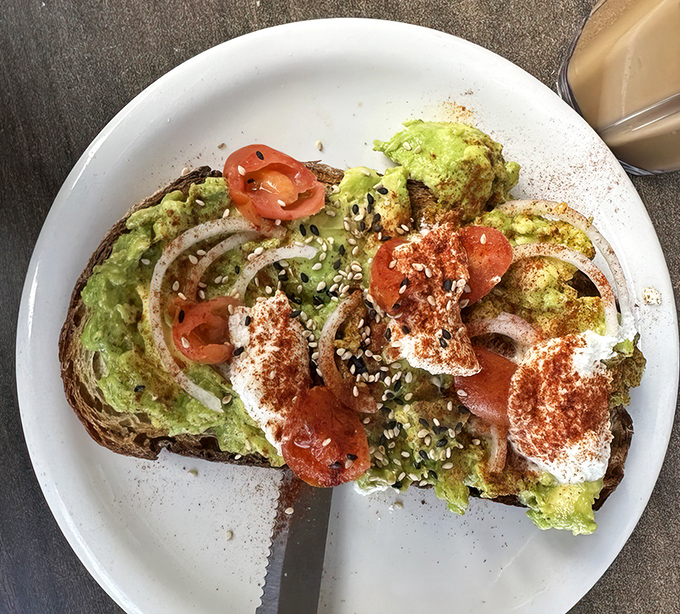 Avocado toast that puts mortgage jokes to shame. Creamy avocado, vibrant tomatoes, and a sprinkle of seeds create a California classic worth every penny.