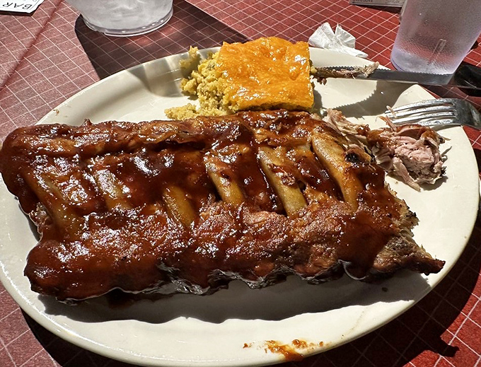 Baby back ribs so tender they practically surrender to your fork, accompanied by that golden square of cornbread that deserves its own fan club.
