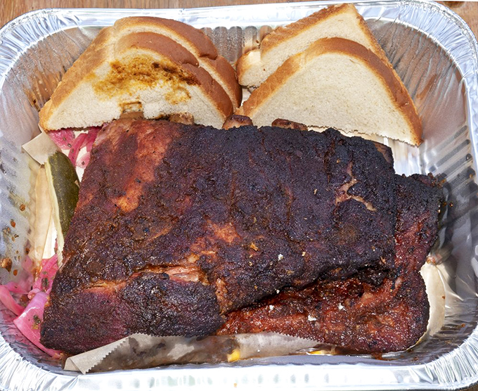 Behold the bark! These ribs wear their spice crust like a badge of honor, with white bread standing by for sauce-sopping duty.