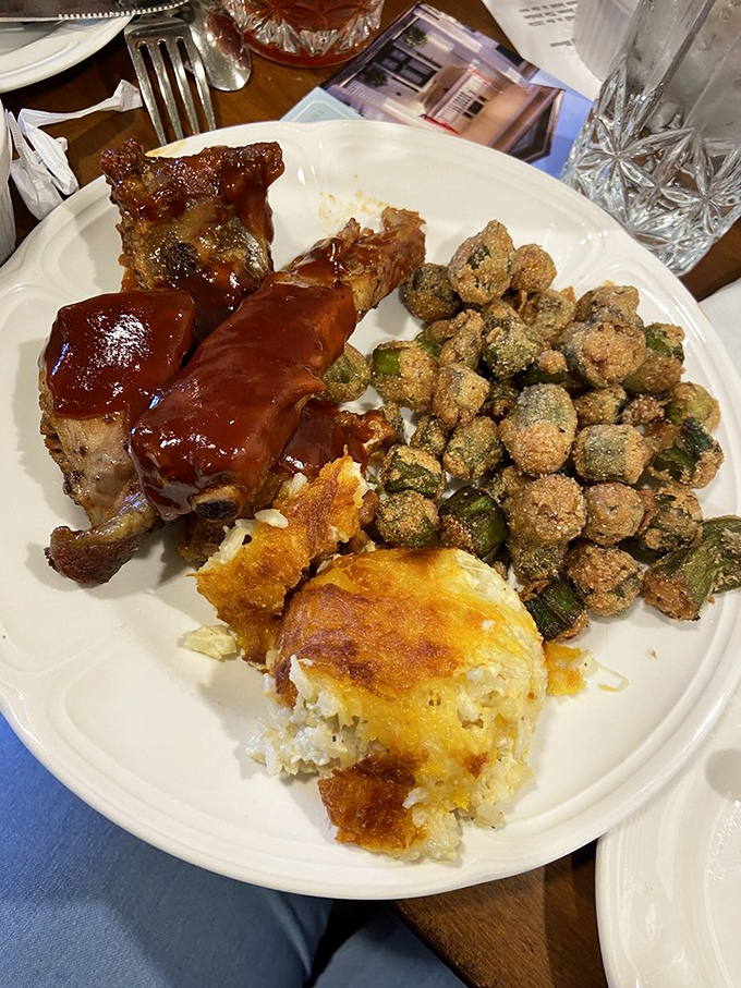 Southern abundance on a plate: tender ribs glazed with tangy sauce, perfectly crisp fried okra, and mac-n-cheese that would make grandma jealous.