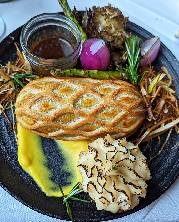 Beef Wellington that's dressed better than most wedding guests, nestled on a plate with vegetables that didn't dare show up underprepared.
