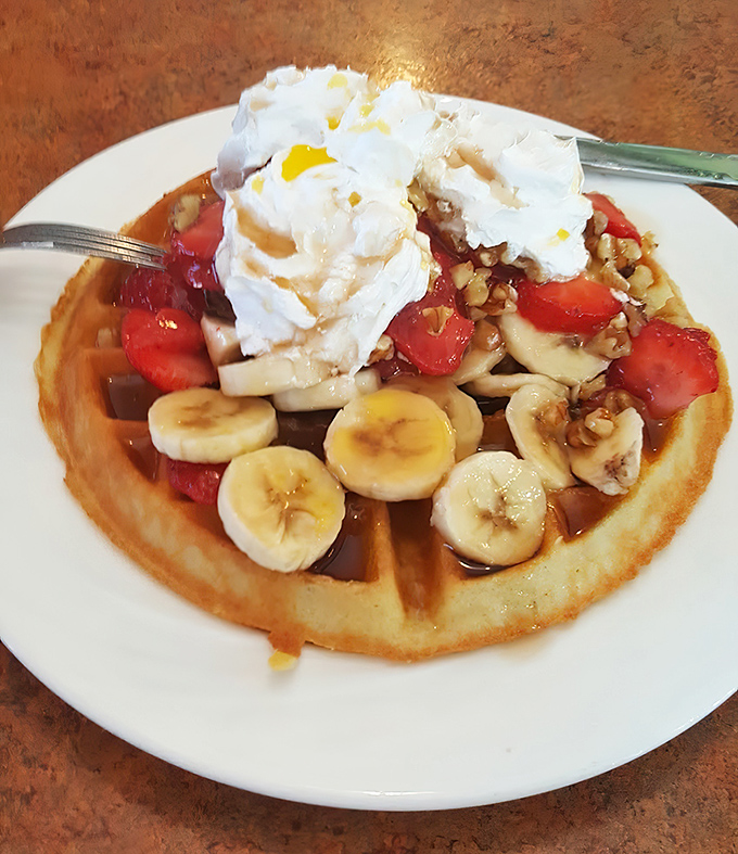 This isn't just a waffle—it's a fruit-topped throne for whipped cream royalty. Bananas and strawberries bringing their A-game.