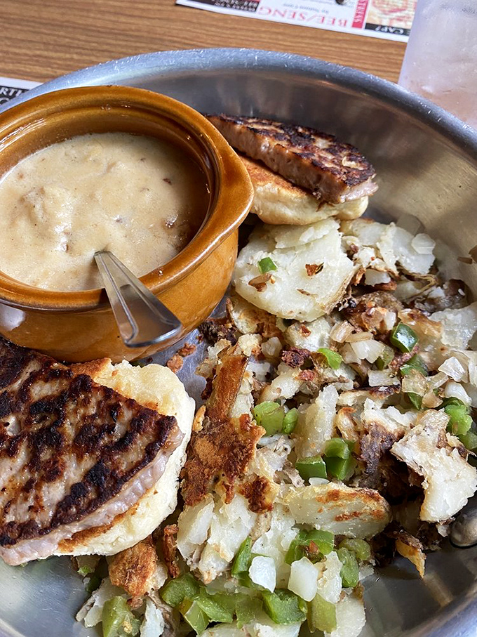 A ceramic crock of sausage gravy alongside home fries that look like they're having the best day ever. Comfort food engineering at its finest.