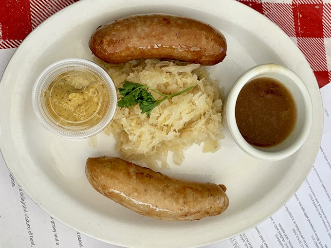 Bratwurst perfection: plump sausages nestled beside tangy sauerkraut. This isn't just lunch&mdash;it's a centuries-old German tradition served on a plate that demands respect.