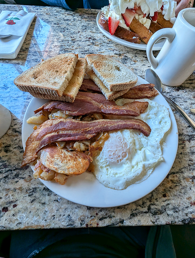 The breakfast trinity&mdash;crispy bacon, sunny eggs, and golden toast&mdash;arranged with the reverence this holy combination deserves. Coffee cup standing by for moral support.