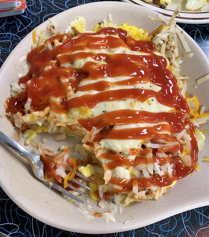 Breakfast architecture at its finest &ndash; layers of eggs, hash browns, and cheese crowned with a zigzag of ketchup that says "Good morning, indeed!"