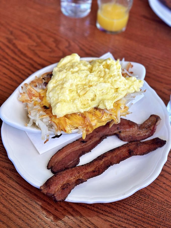 The breakfast trifecta: fluffy scrambled eggs, crispy hash browns with melted cheese, and bacon cooked to that perfect point between chewy and crisp.