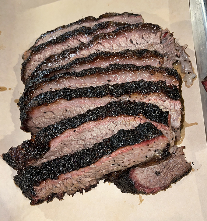 Brisket sliced thicker than a Michigan winter coat, with a pepper-crusted exterior that gives way to meat so tender it practically surrenders at the sight of your fork.