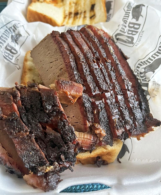 The brisket sports a perfect smoke ring and peppery bark that gives way to meat so tender it practically dissolves on your tongue.