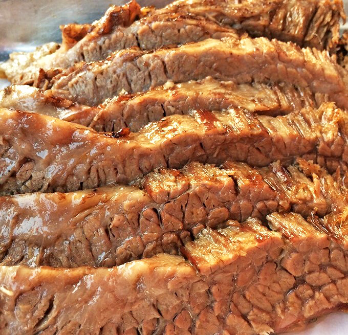 Brisket sliced so perfectly you could frame it, with a smoke ring that tells the story of patience and proper technique.