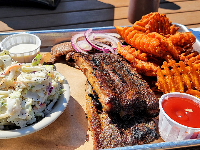 BBQ trinity on full display: perfectly smoked brisket with that telltale smoke ring, creamy coleslaw, and those waffle-cut sweet potato fries that haunt your dreams.