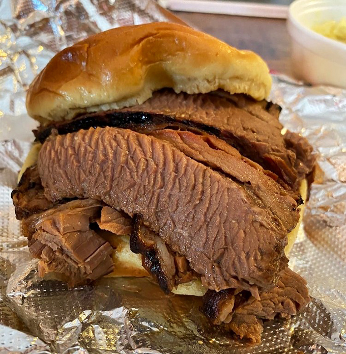 This isn't just a brisket sandwich; it's an architectural marvel of smoke-kissed beef with a bark so perfect it deserves its own appreciation society.