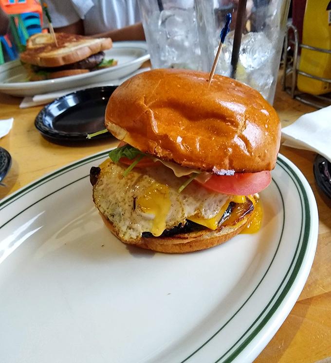 This burger arrives like a delicious architectural marvel, demanding both hands and your complete, undivided attention for proper consumption.