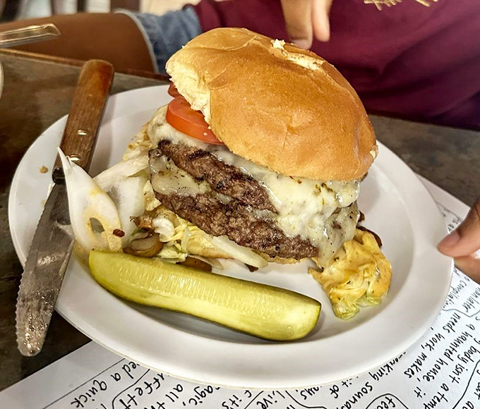 This isn't just a burger&mdash;it's a towering monument to beef artistry. The pickle stands guard, knowing you'll need reinforcements to tackle this beauty. 