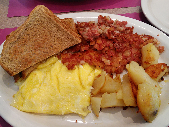 Breakfast perfection on a plate: fluffy scrambled eggs, crispy corned beef hash, and home fries that could make a potato proud.