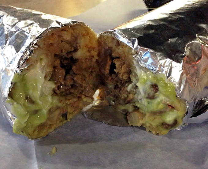 Behold the cross-section of happiness—a burrito revealing its inner secrets like a delicious geological formation where each layer tells a story of flavor.