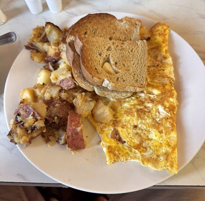 Breakfast perfection: a golden omelet that's somehow both fluffy and substantial, home fries with crispy edges, and toast that's actually worth eating.
