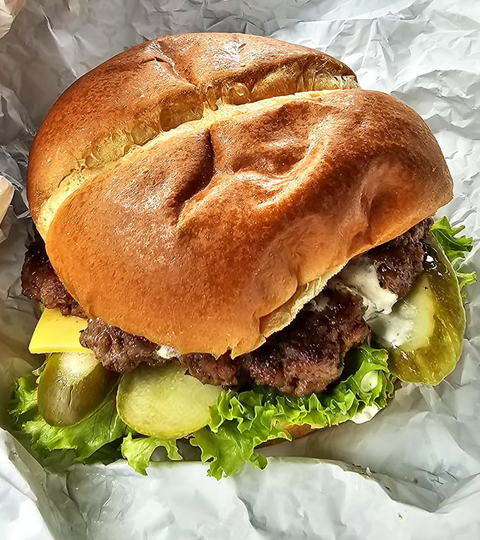 This isn't just a burger—it's an architectural masterpiece of beef, cheese, and fresh toppings on a perfectly toasted bun that demands a two-handed commitment.