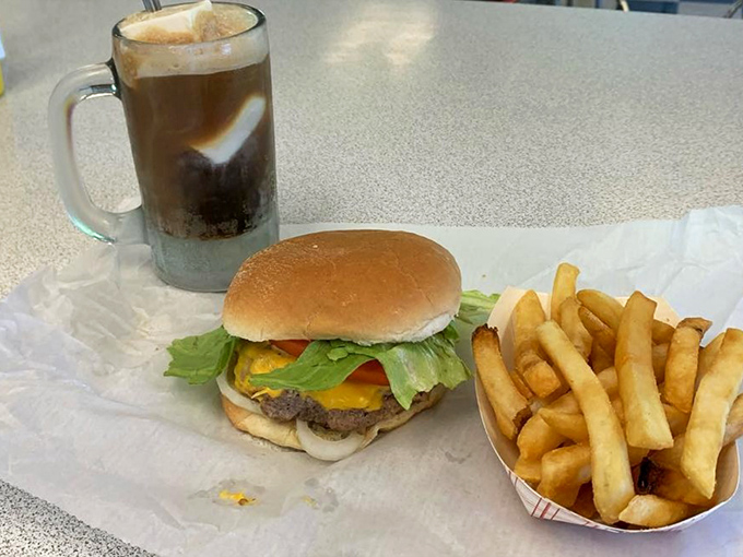 The holy trinity of American comfort: a perfectly grilled burger, crispy fries, and a frosty mug of root beer. No filter needed on this kind of beauty.
